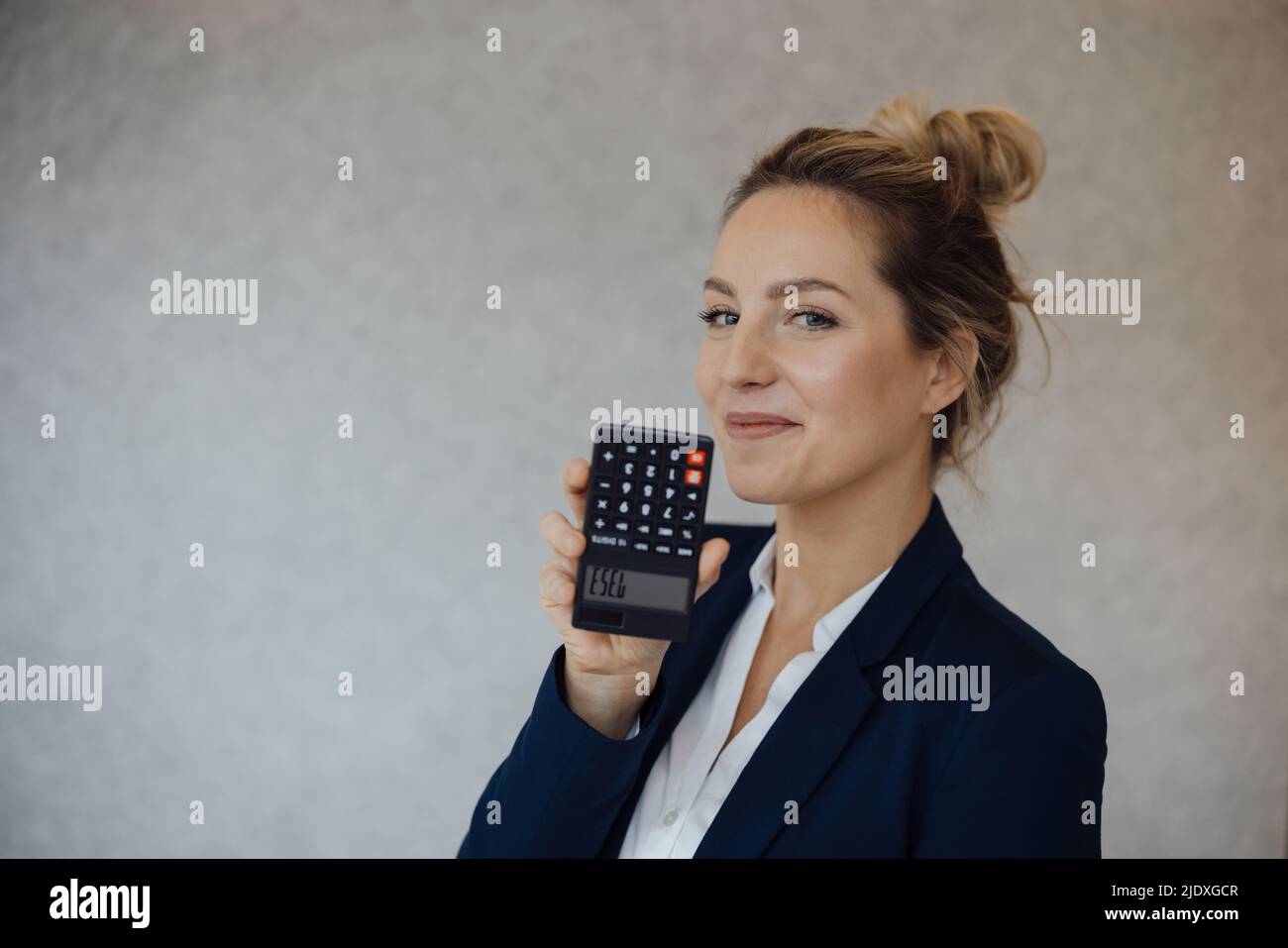 Smiling businesswoman showing donkey text on upside down calculator in ...
