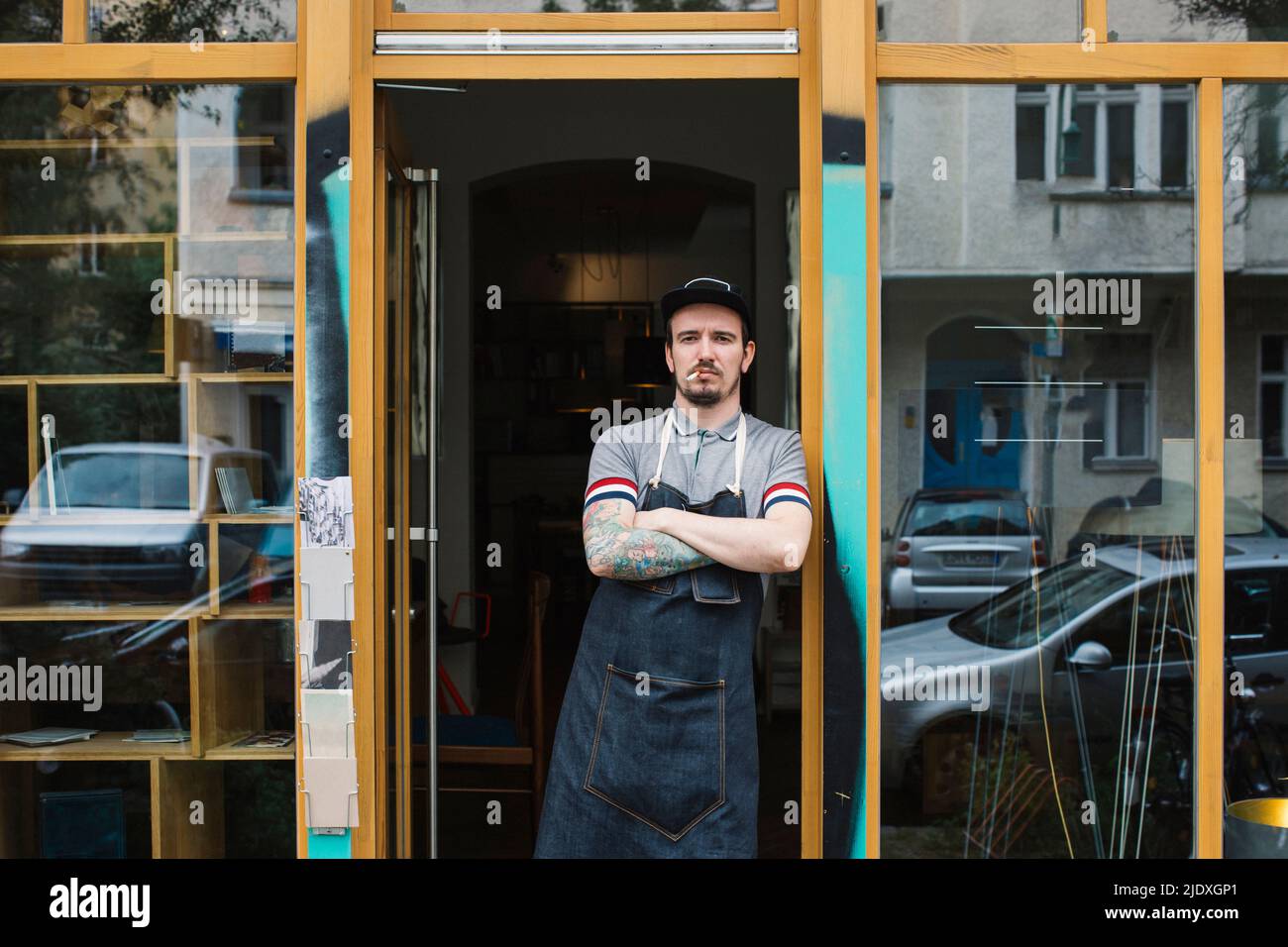 Barber standing with arms crossed at doorway of salon Stock Photo - Alamy