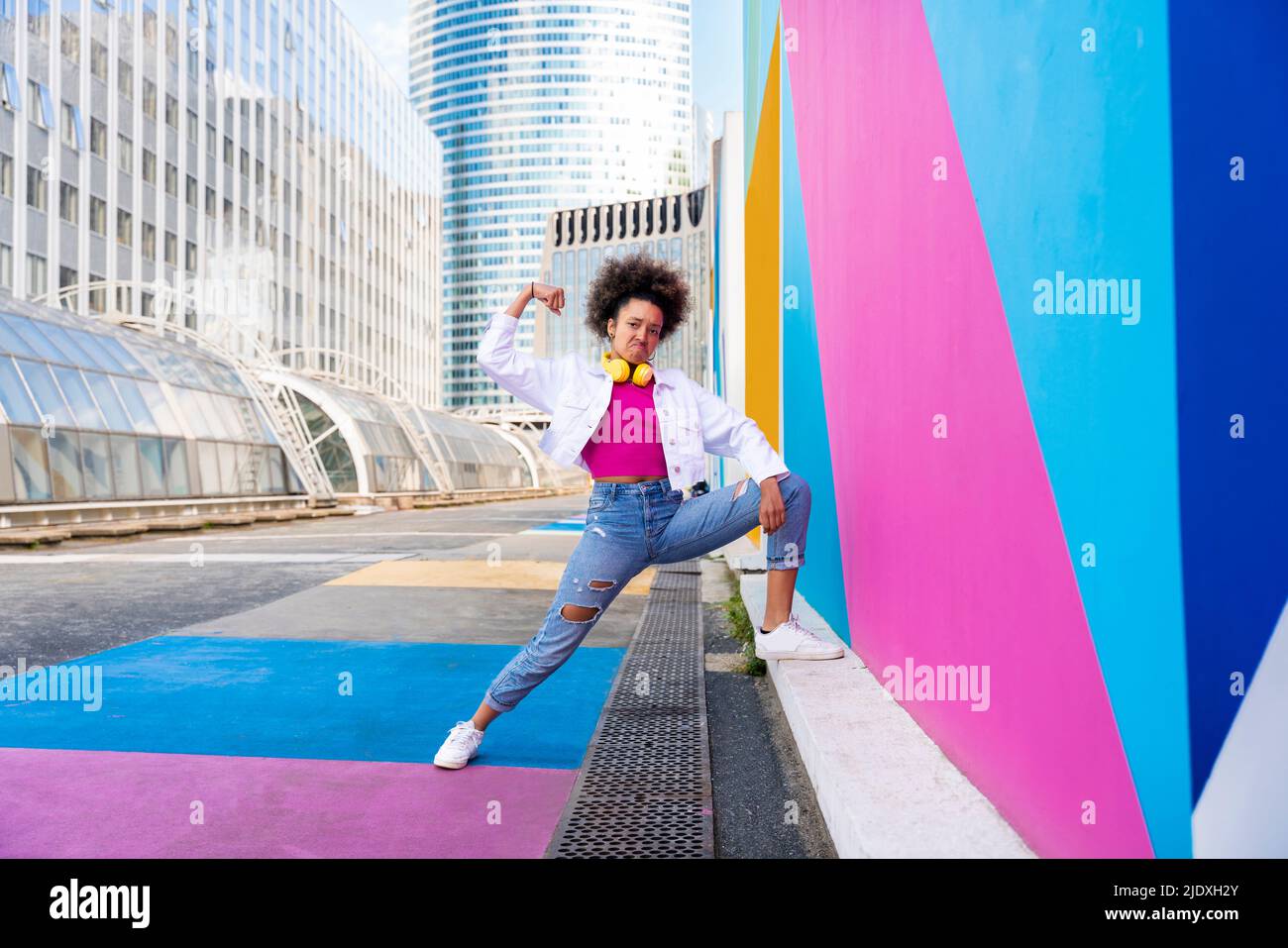 Afro woman flexing muscles by colorful wall Stock Photo - Alamy