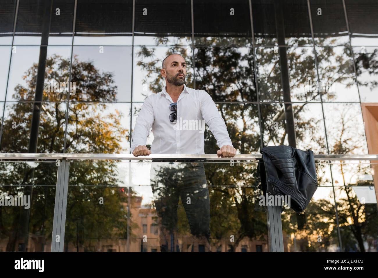 Man leaning on glass railing in front of building Stock Photo - Alamy