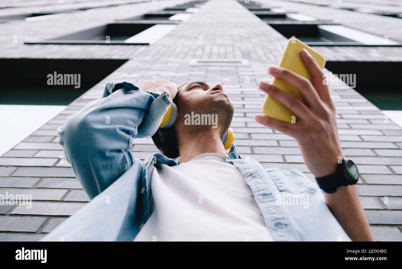 Man holding mobile phone standing by building wall Stock Photo - Alamy