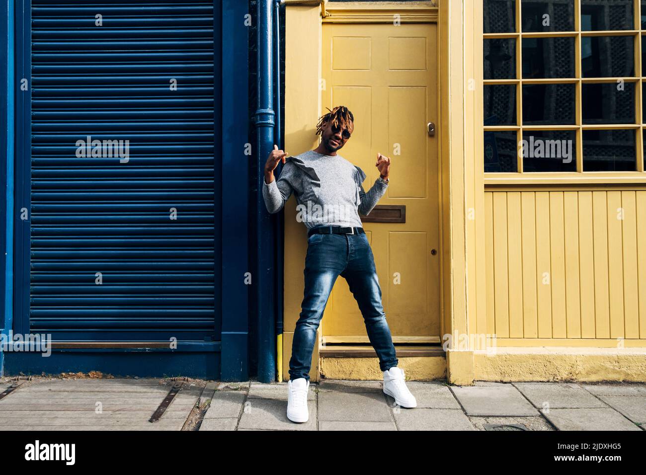 Young man standing in front of building on footpath Stock Photo - Alamy