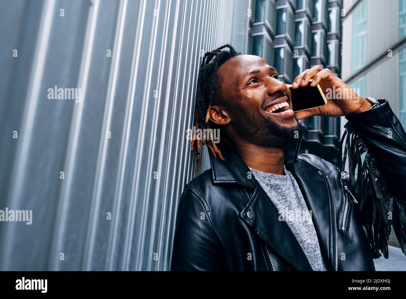 Happy man talking on mobile phone by wall Stock Photo - Alamy