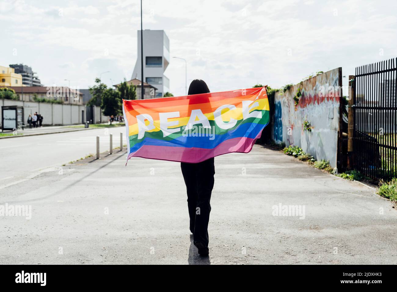 Young woman with rainbow flag walking on road Stock Photo - Alamy