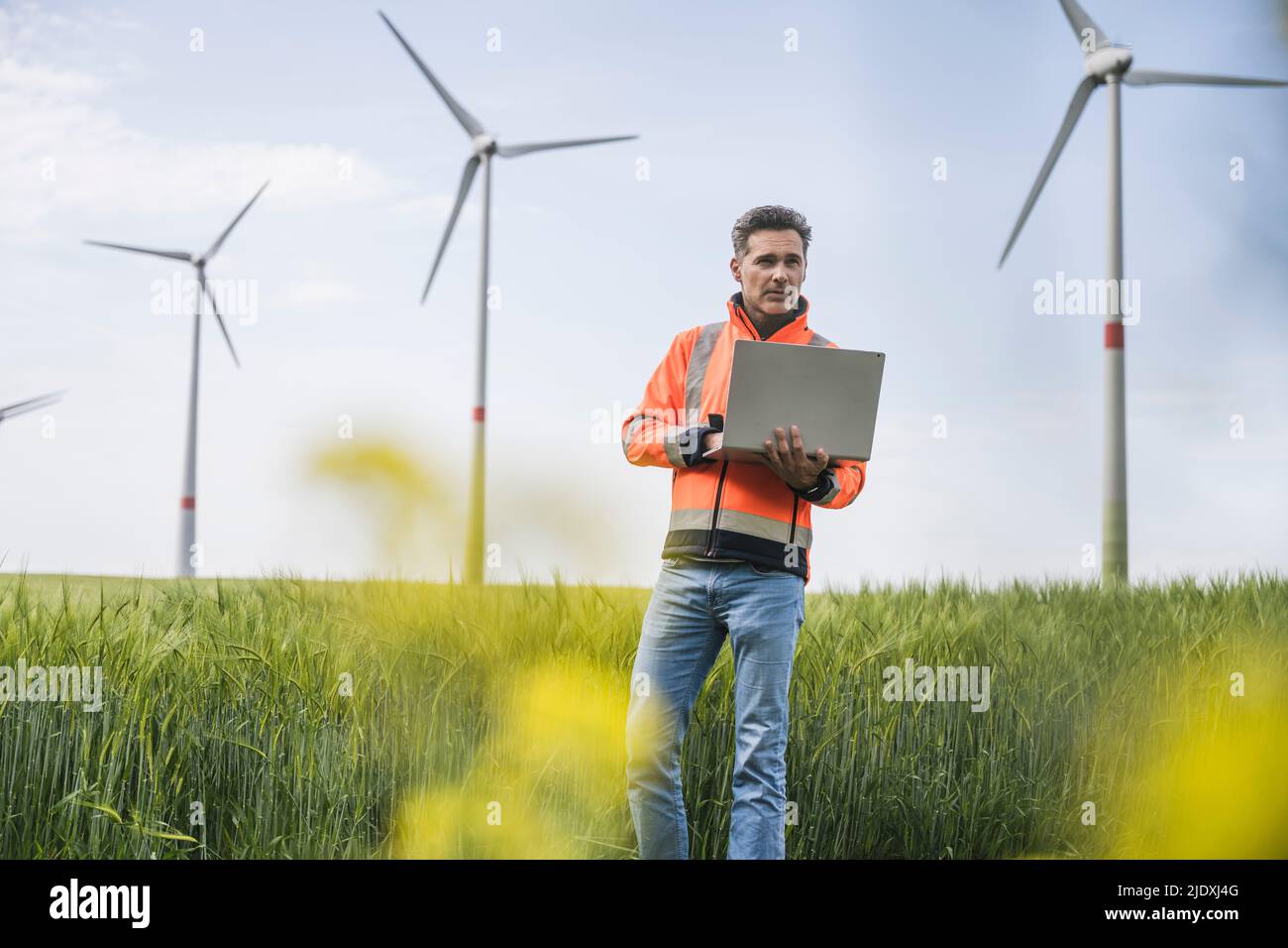 Engineer holding laptop standing in front of wind turbines Stock Photo ...