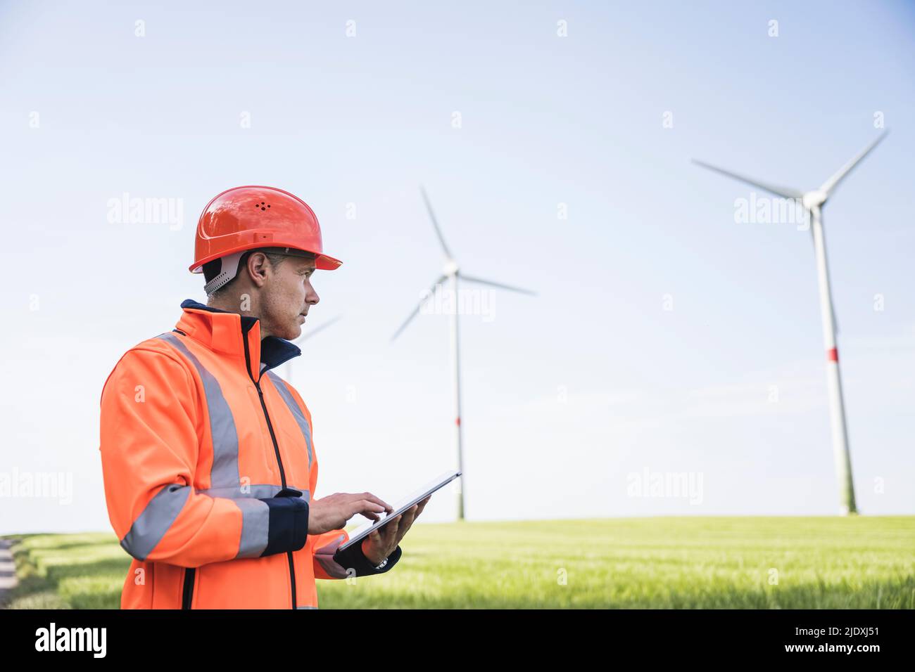 Engineer holding tablet PC at field wind turbine Stock Photo - Alamy