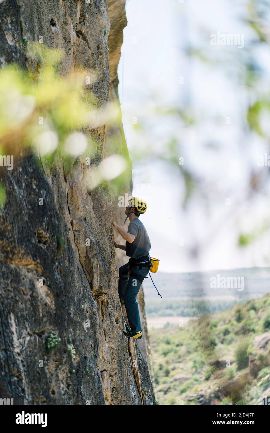 Determined man climbing mountain rock wall Stock Photo - Alamy