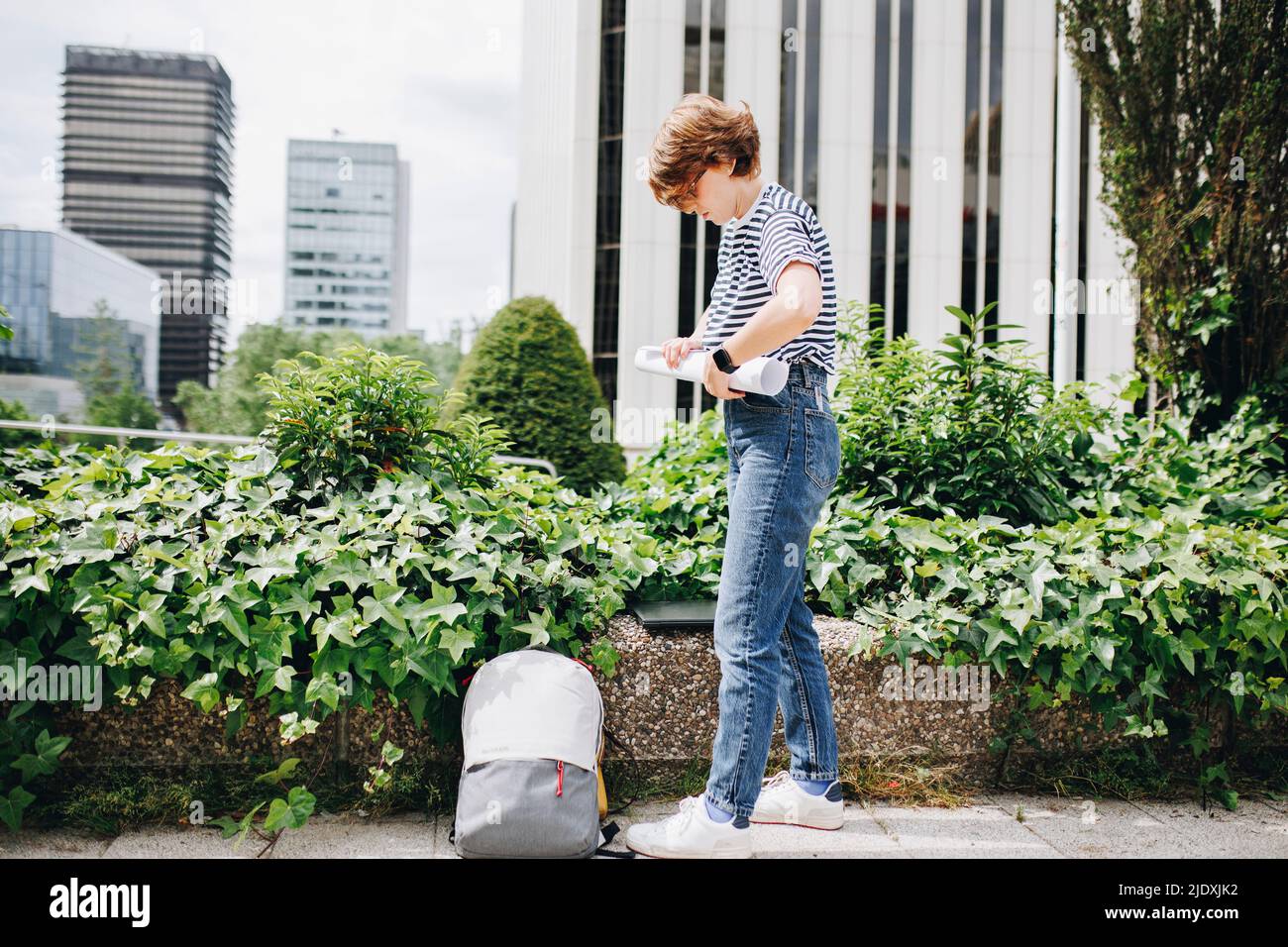 Architect rolling blueprints standing near plants Stock Photo - Alamy