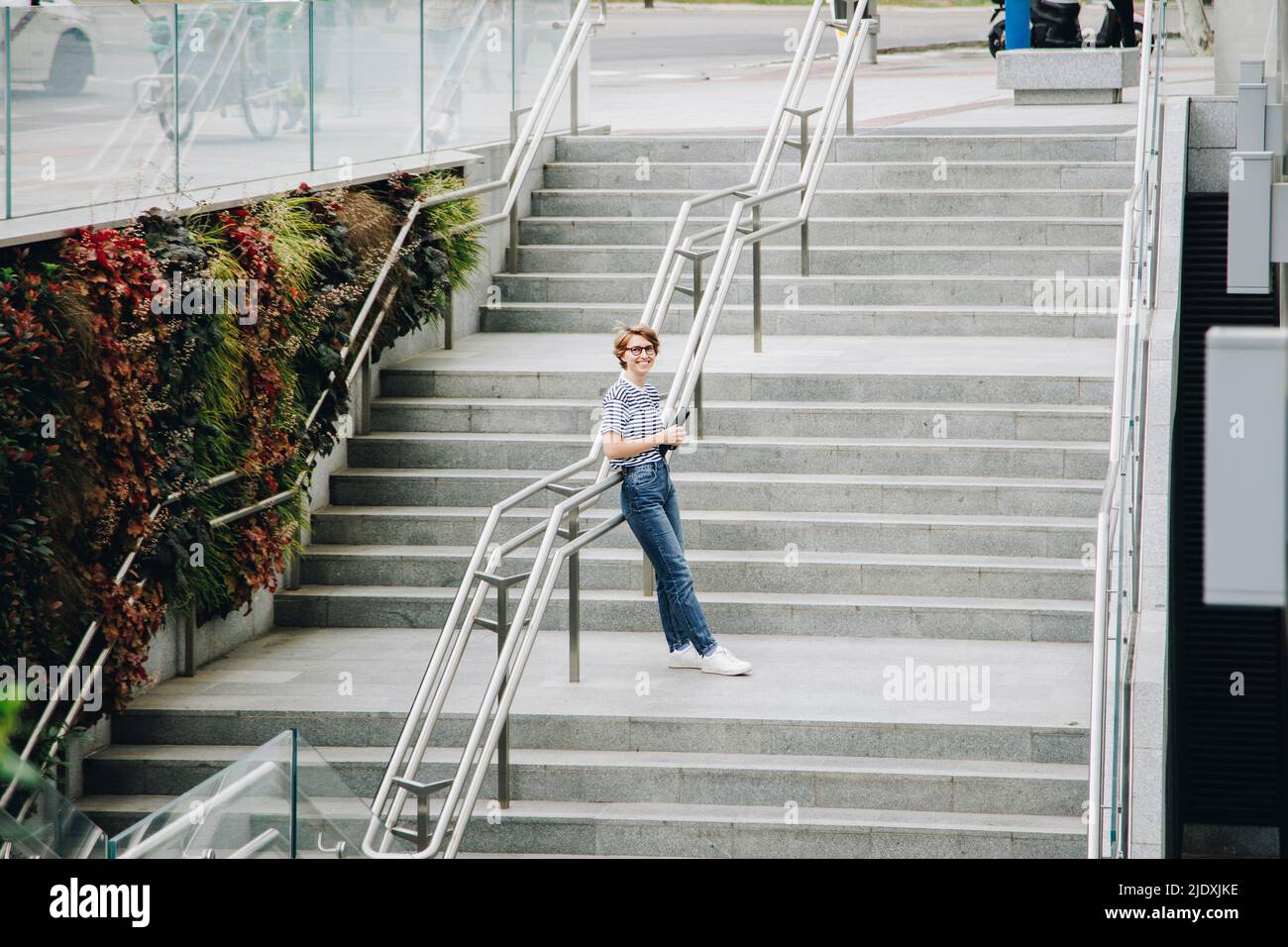 Happy woman leaning on railing at staircase Stock Photo - Alamy