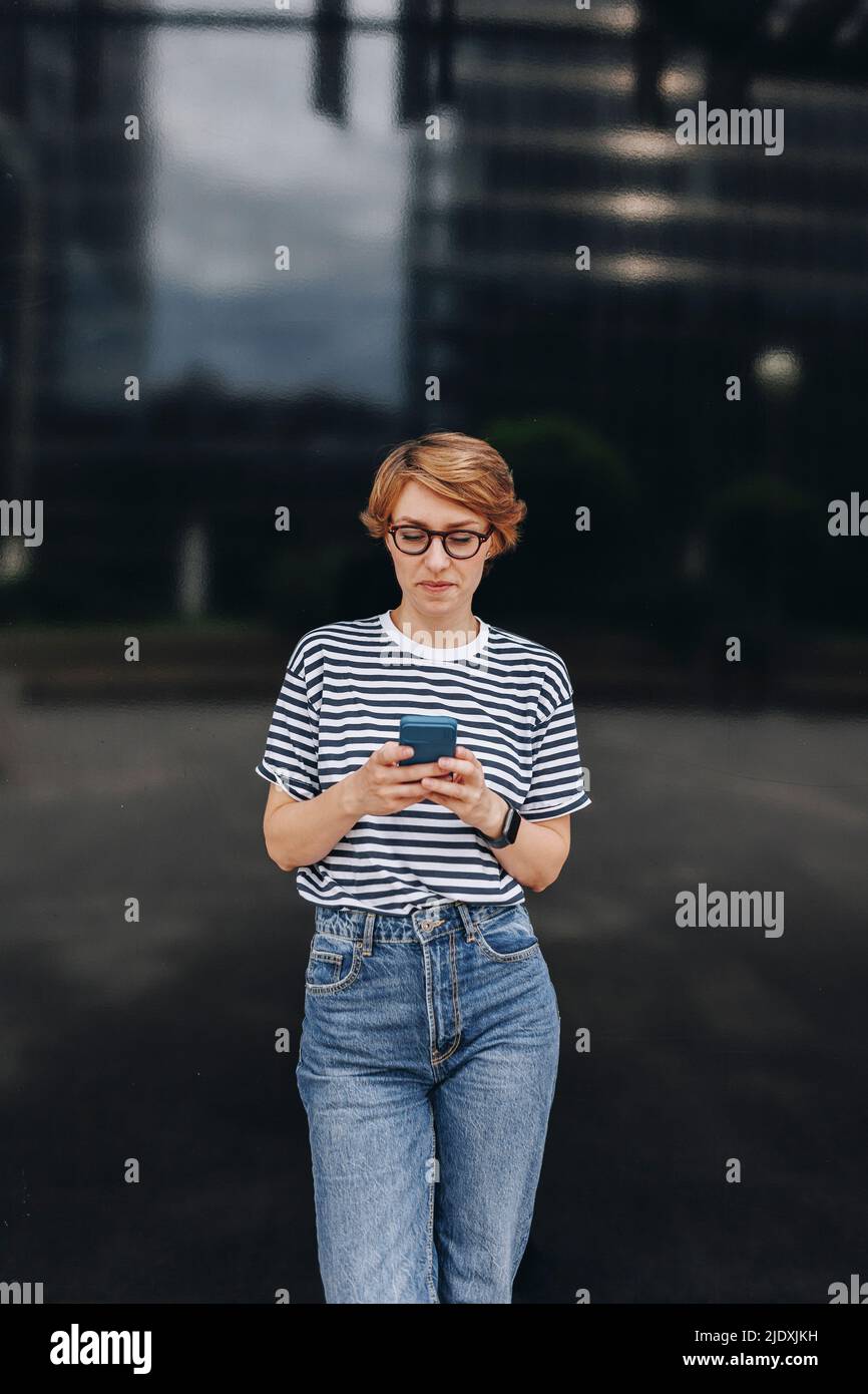 Woman using smart phone standing in front of black wall Stock Photo - Alamy