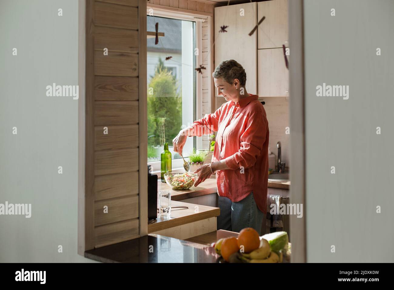 Woman at the window in kitchen preparing salad Stock Photo - Alamy