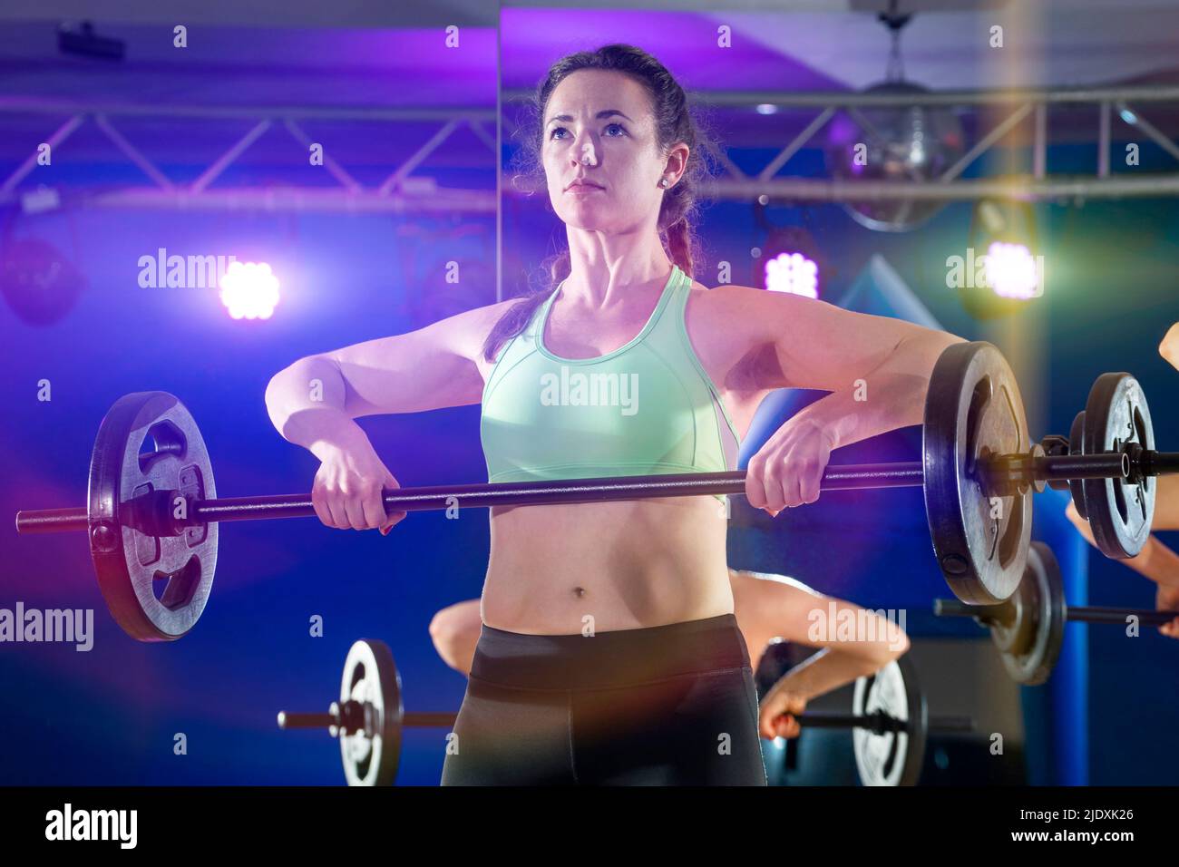 Woman lifting barbell at health club Stock Photo - Alamy