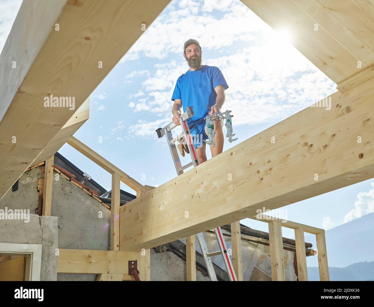 Young man standing on ladder at construction site Stock Photo - Alamy