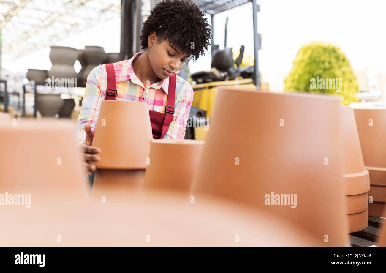 Gardener stacking pots at nursery warehouse Stock Photo - Alamy