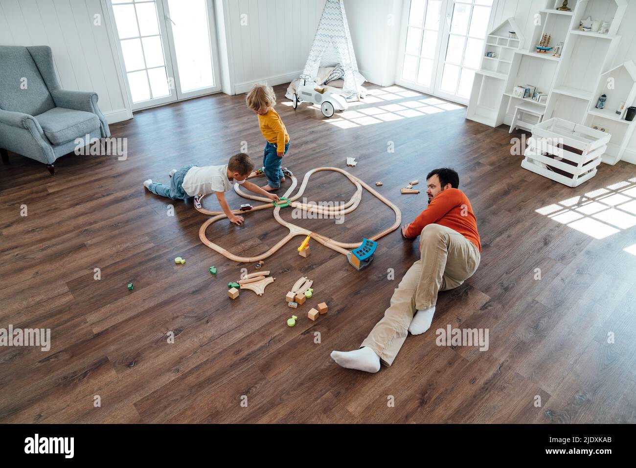 Father lying on floor by son playing with toy train set at home Stock ...