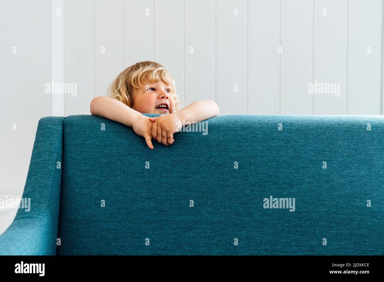 Cute boy standing behind sofa in living room at home Stock Photo - Alamy