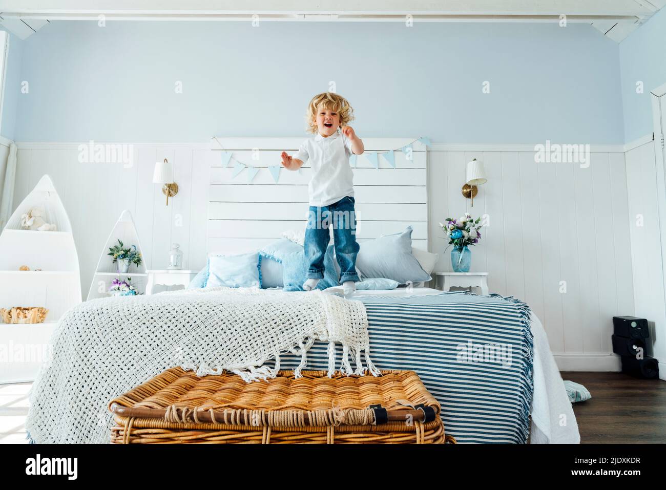 Cute boy jumping on bed at home Stock Photo - Alamy