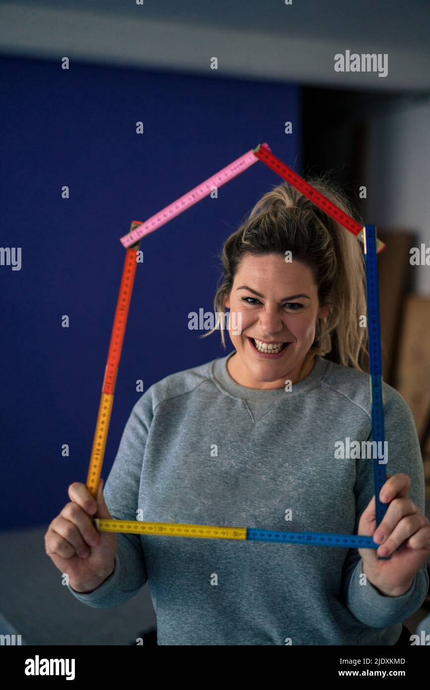Happy woman holding ruler house model at home Stock Photo - Alamy