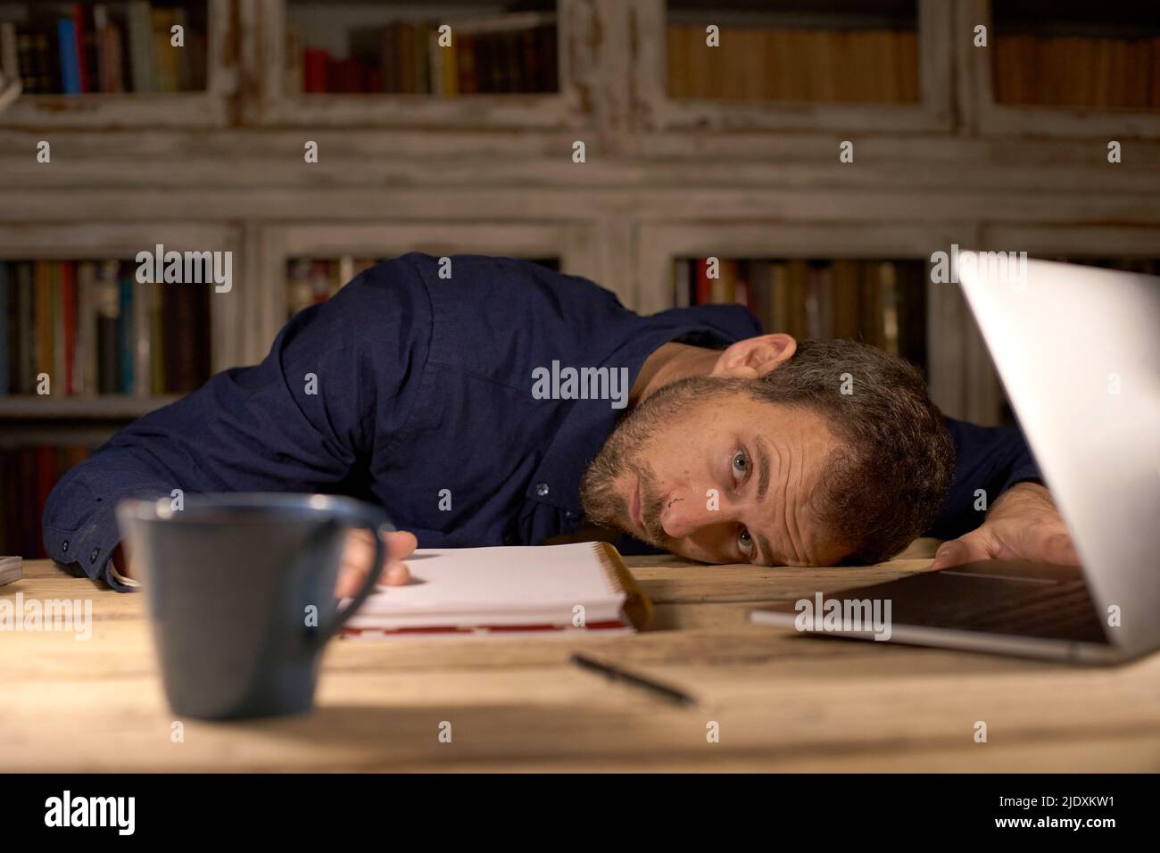 Tired businessman with head on desk at home Stock Photo - Alamy