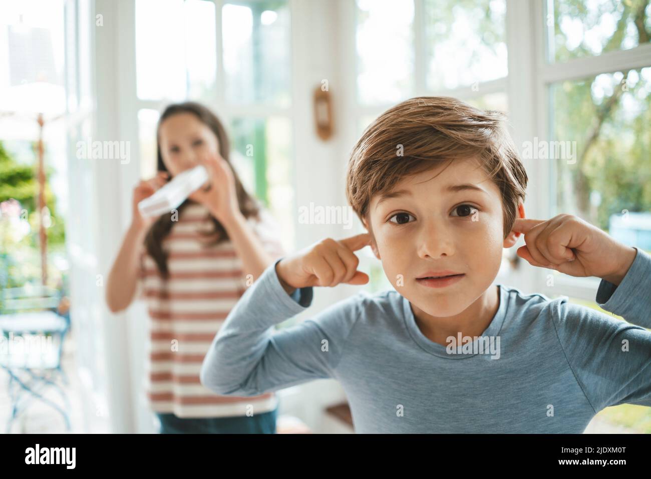 Boy standing with fingers in ears at home Stock Photo - Alamy