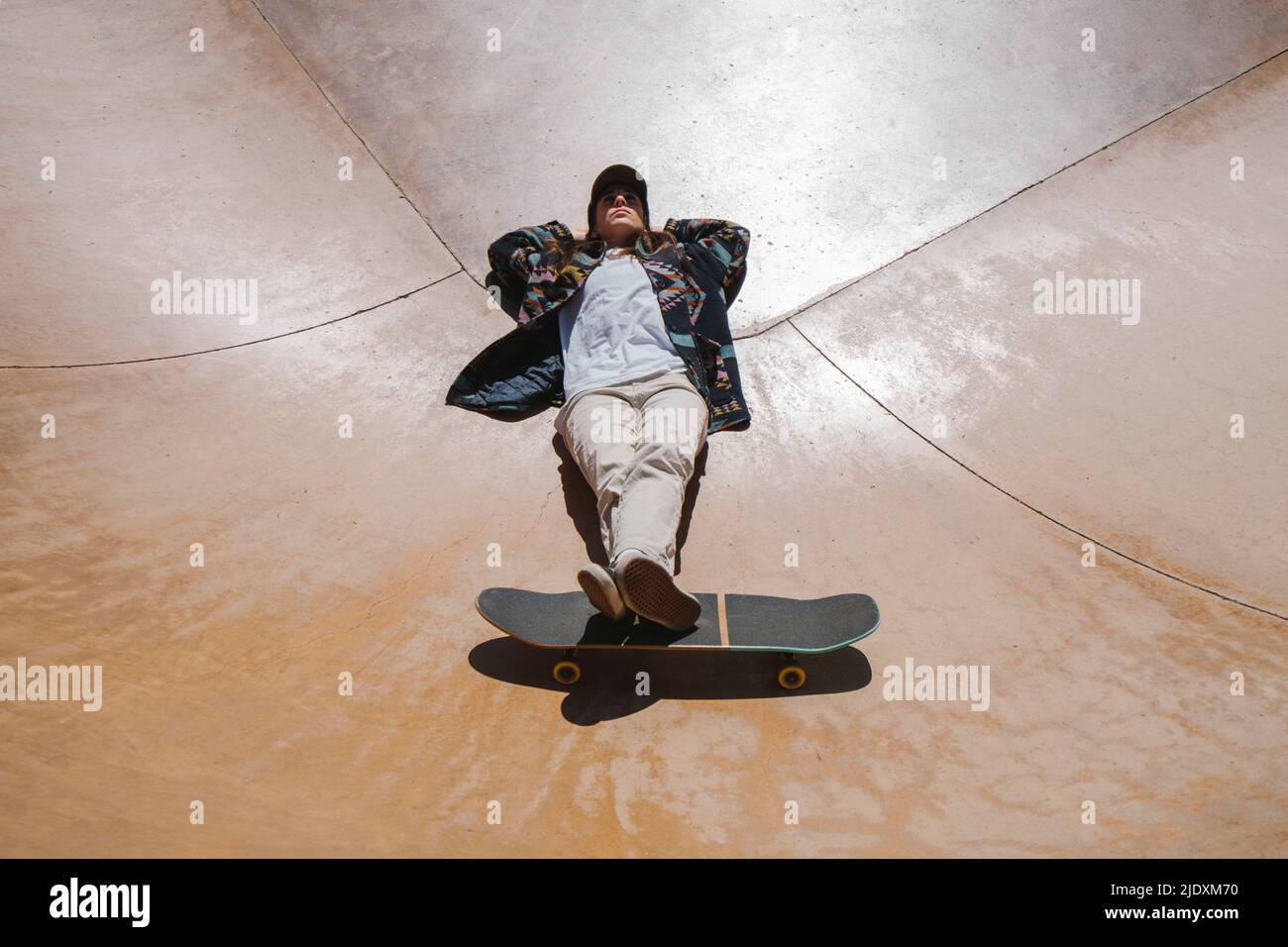 Young woman with hands behind head lying on sports ramp Stock Photo - Alamy