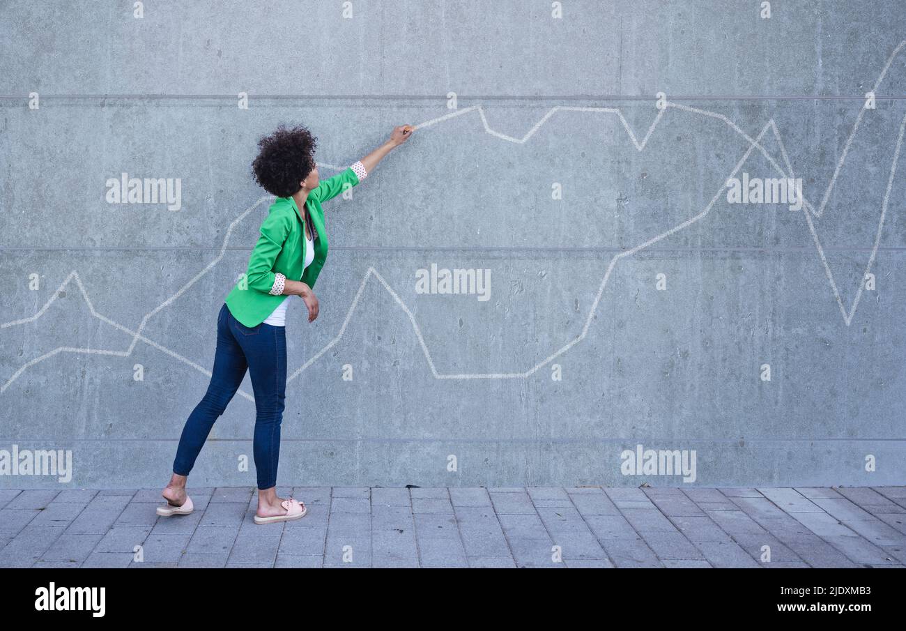 Young woman pointing at chart painted on wall Stock Photo - Alamy