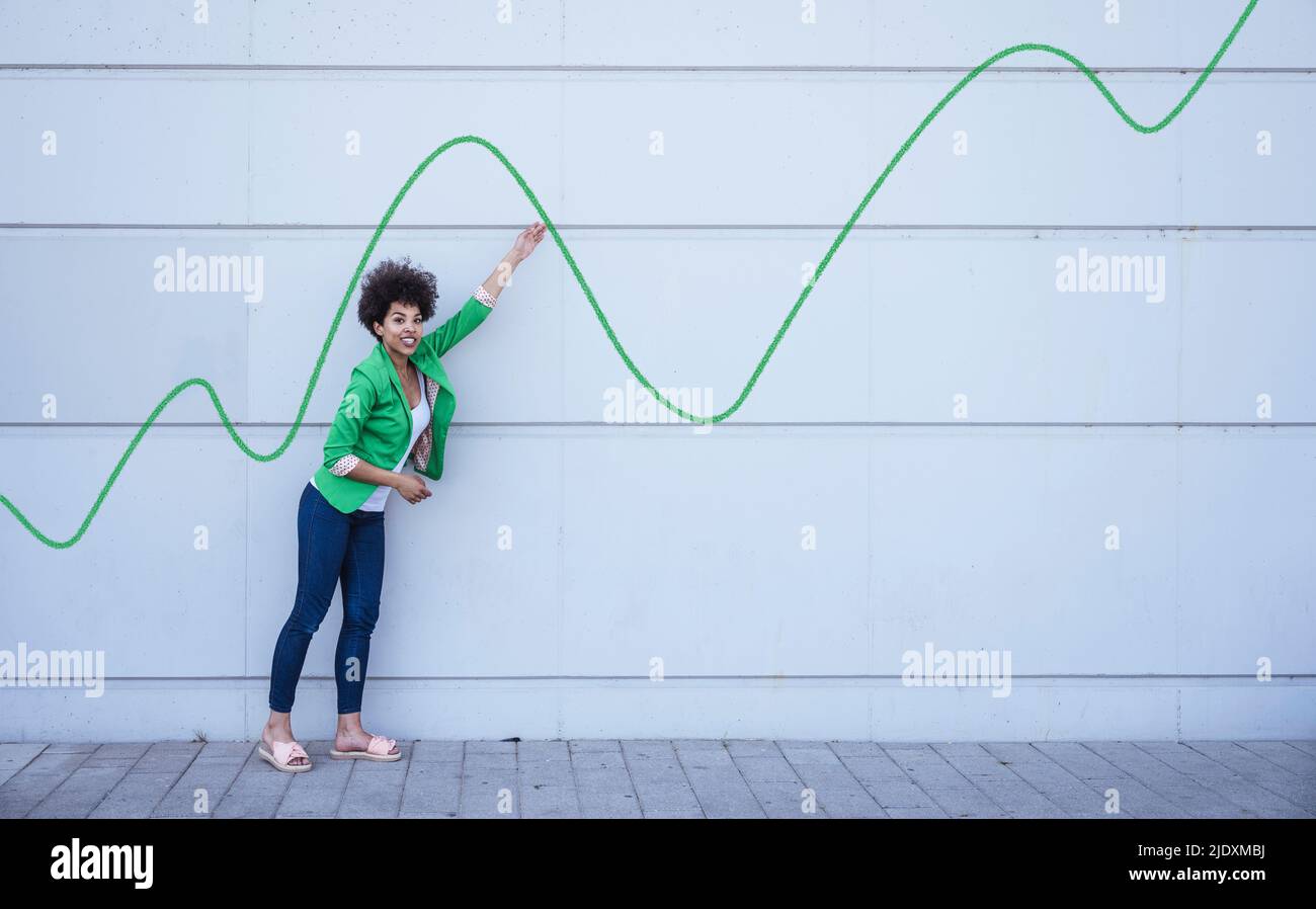 Young woman pointing at chart painted on wall Stock Photo - Alamy