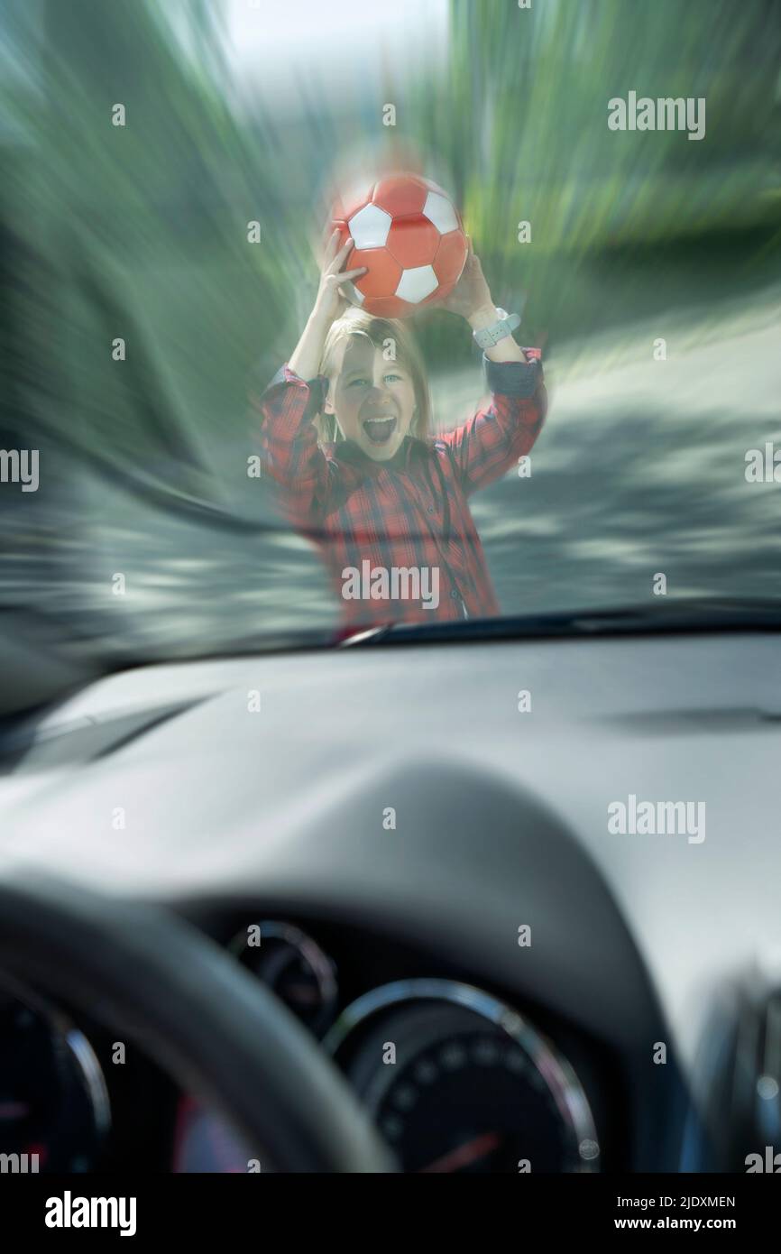 Scared boy with ball seen through windshield of car trying to prevent ...