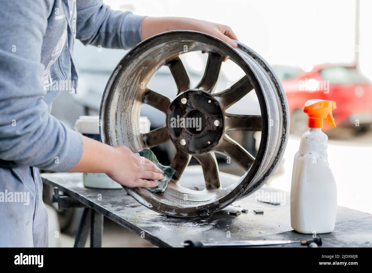 Hands of mechanic cleaning wheel in workshop Stock Photo - Alamy
