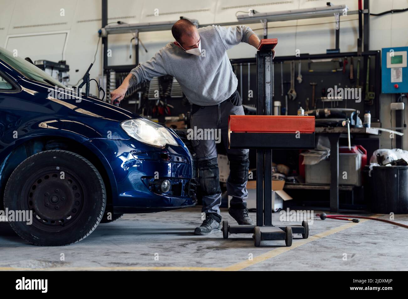 Auto technician checking headlight by car at repair garage Stock Photo ...