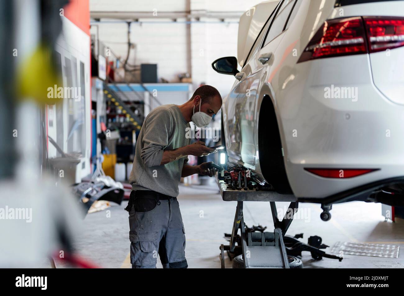 Mechanic photographing car part in garage Stock Photo - Alamy