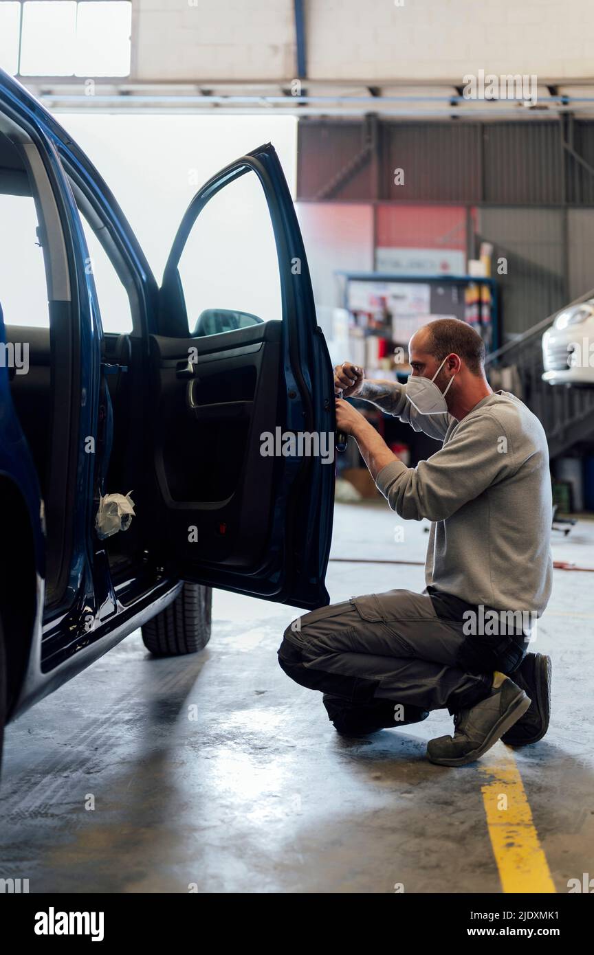 Auto mechanic working on car door in repair shop Stock Photo - Alamy