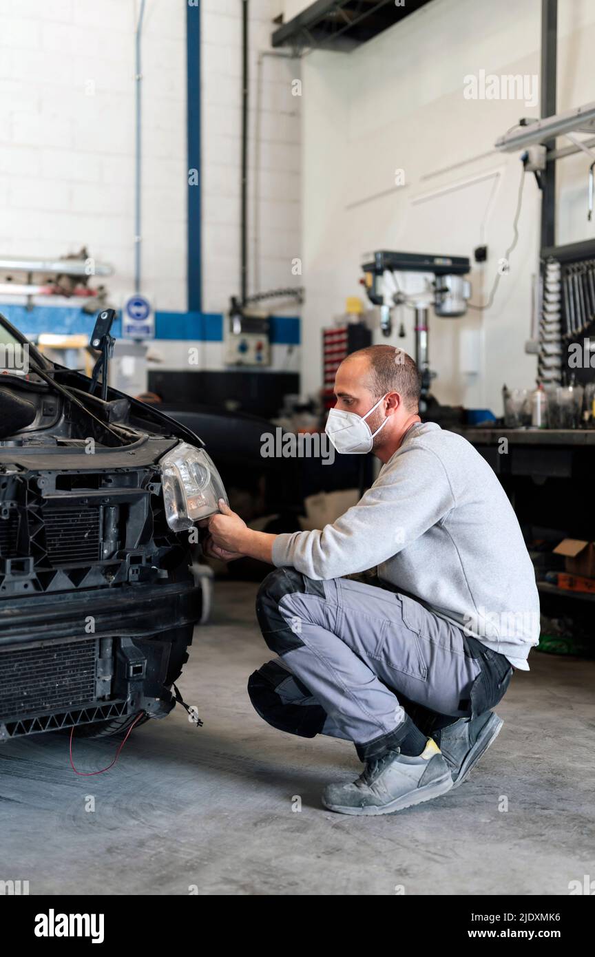 Auto mechanic analyzing headlight in workshop Stock Photo - Alamy