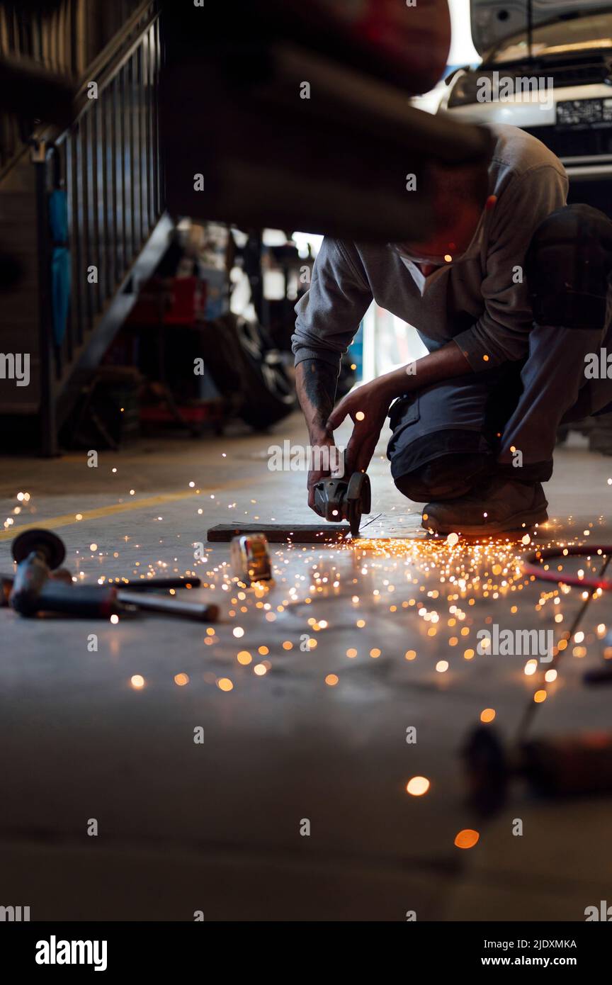 Repairman cutting metal on floor in auto workshop Stock Photo - Alamy