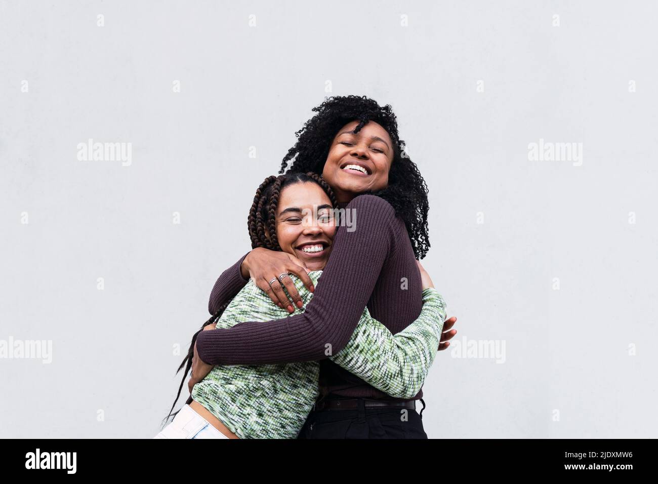 Happy friends hugging each other in front of white wall Stock Photo - Alamy