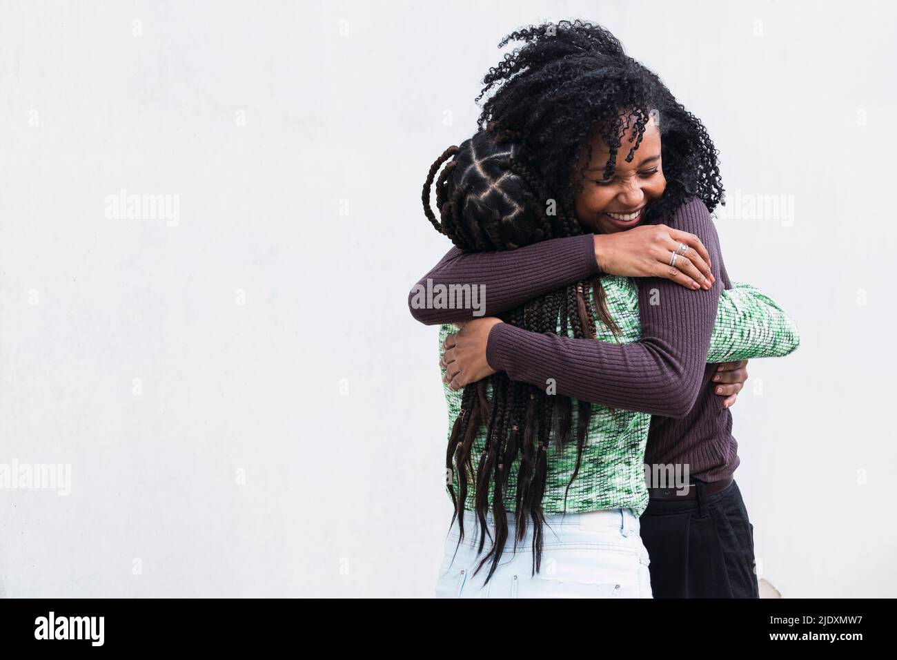 Happy friends hugging in front of white wall Stock Photo - Alamy
