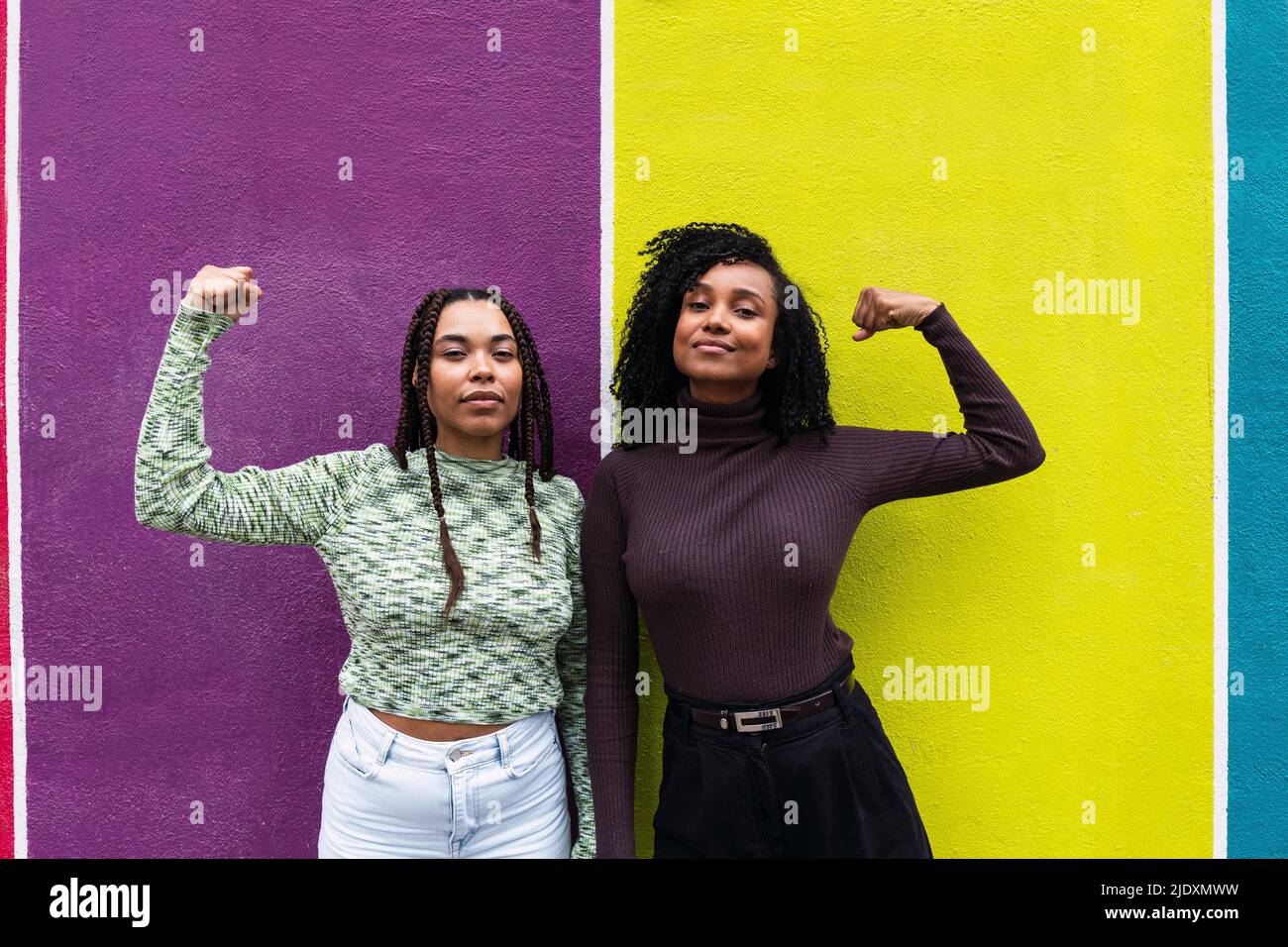 Smiling friends flexing muscles in front of wall Stock Photo - Alamy