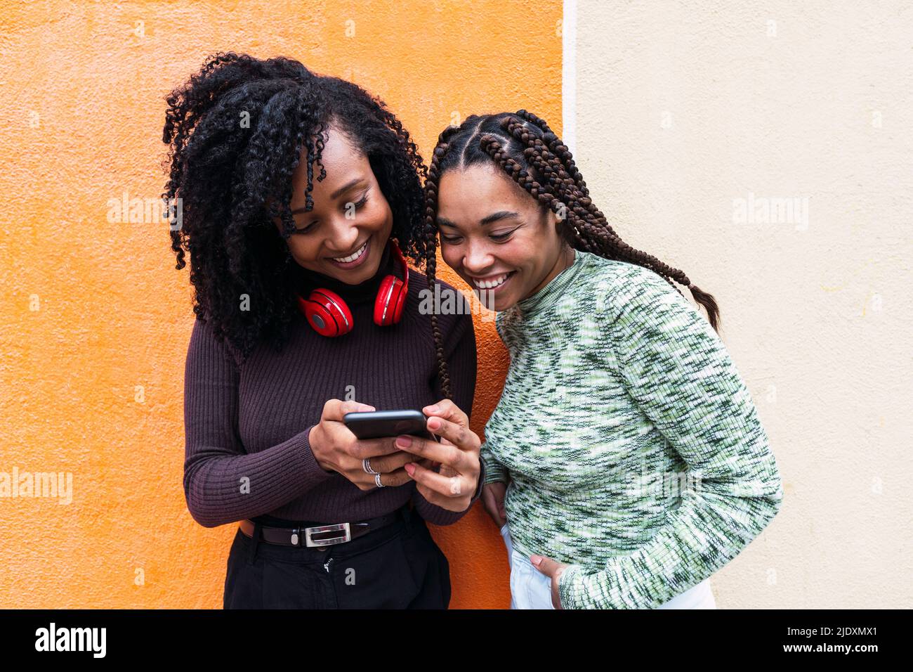 Happy multiracial friends sharing mobile phone standing in front of ...