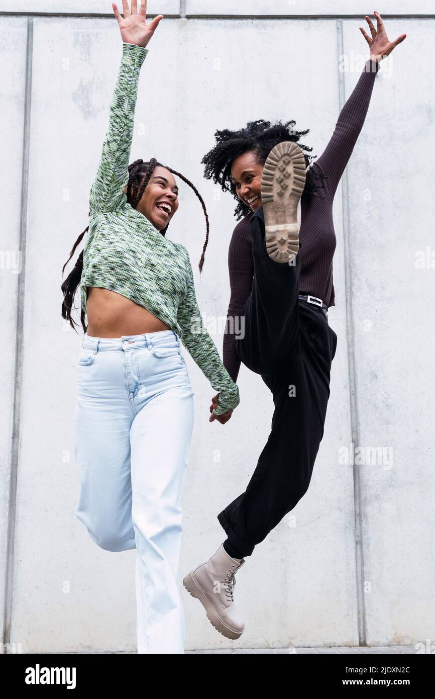 Happy friends holding hands jumping hi-res stock photography and images ...