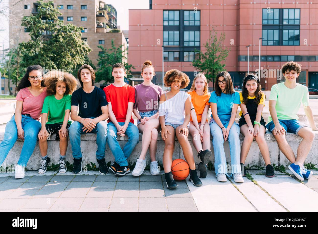 Friends sitting together in front of building Stock Photo - Alamy