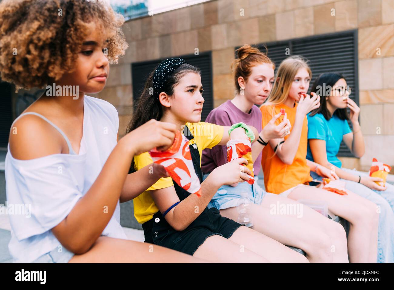 Friends sitting together eating snacks Stock Photo - Alamy