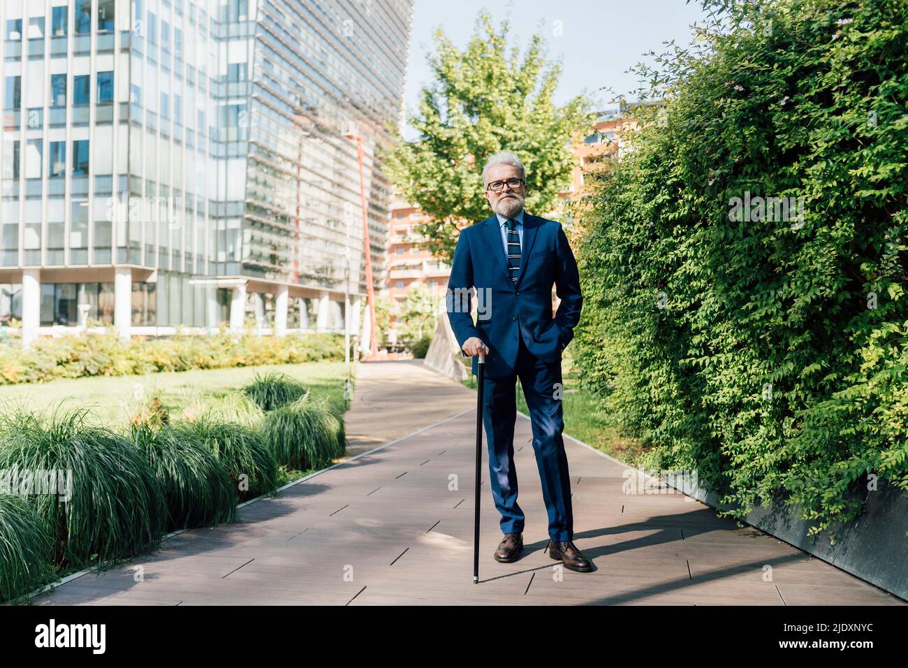 Senior businessman standing with cane outside office building Stock ...
