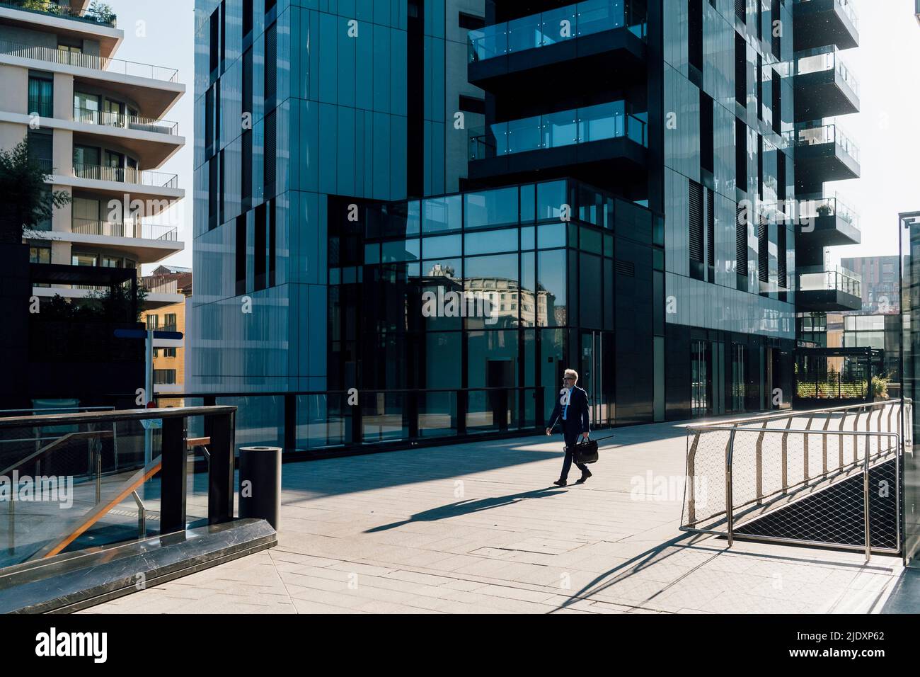 Businessman walking with briefcase outside office building Stock Photo ...