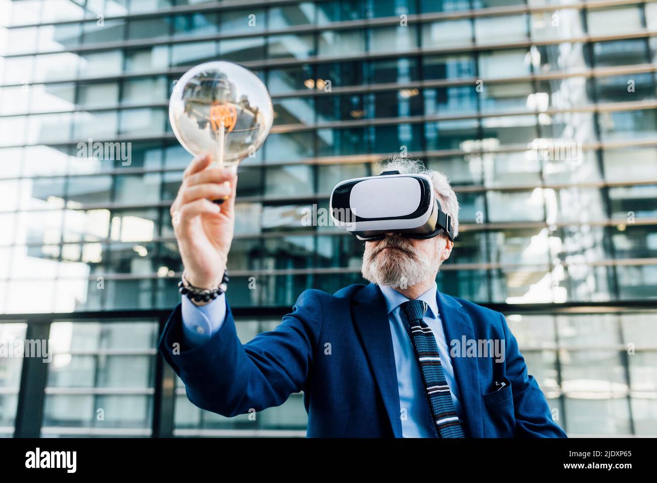 Senior businessman with virtual reality simulator holding light bulb ...