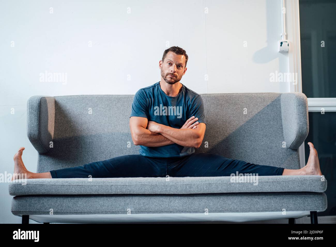 Man stretching legs sitting with arms crossed on sofa at home Stock ...