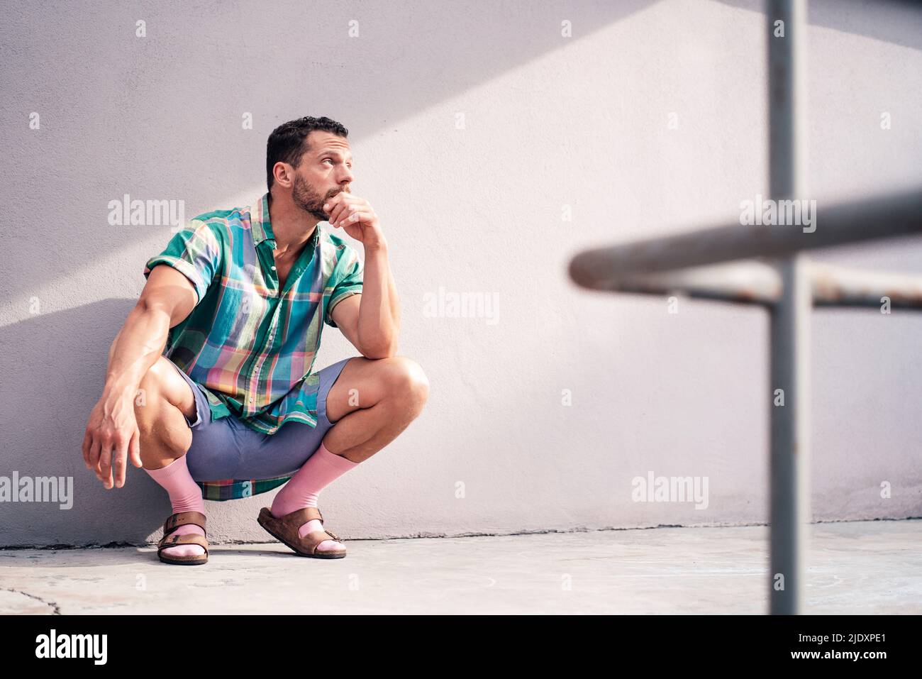 Thoughtful man crouching near concrete wall Stock Photo - Alamy
