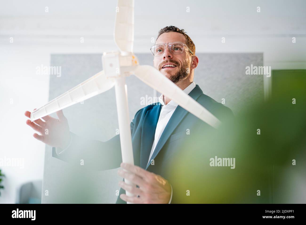 Happy businessman touching blade of windmill model in office Stock ...