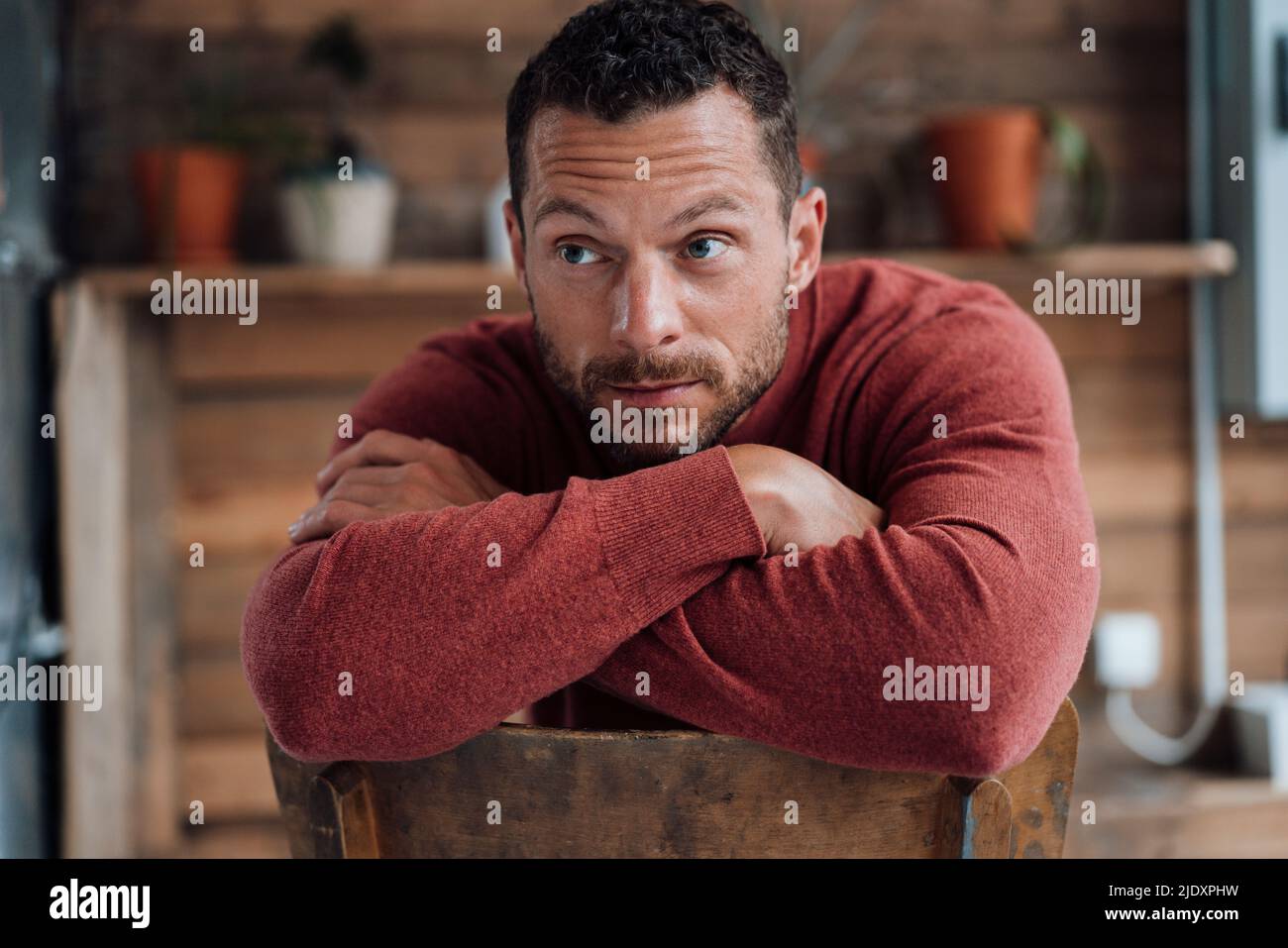 Contemplated man with head resting on arms sitting on chair Stock Photo ...
