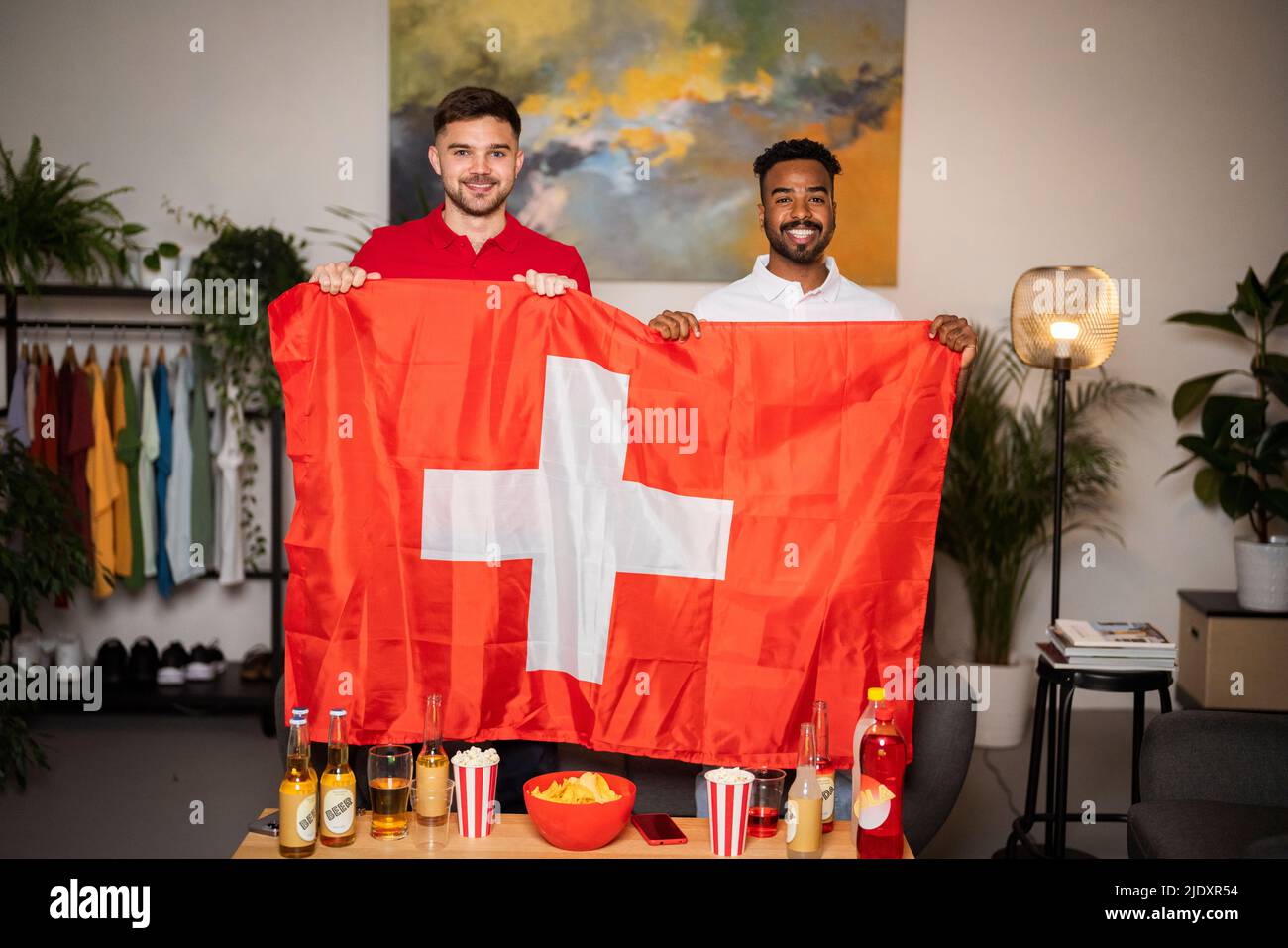 Happy football fans standing with Swiss flag at home Stock Photo - Alamy