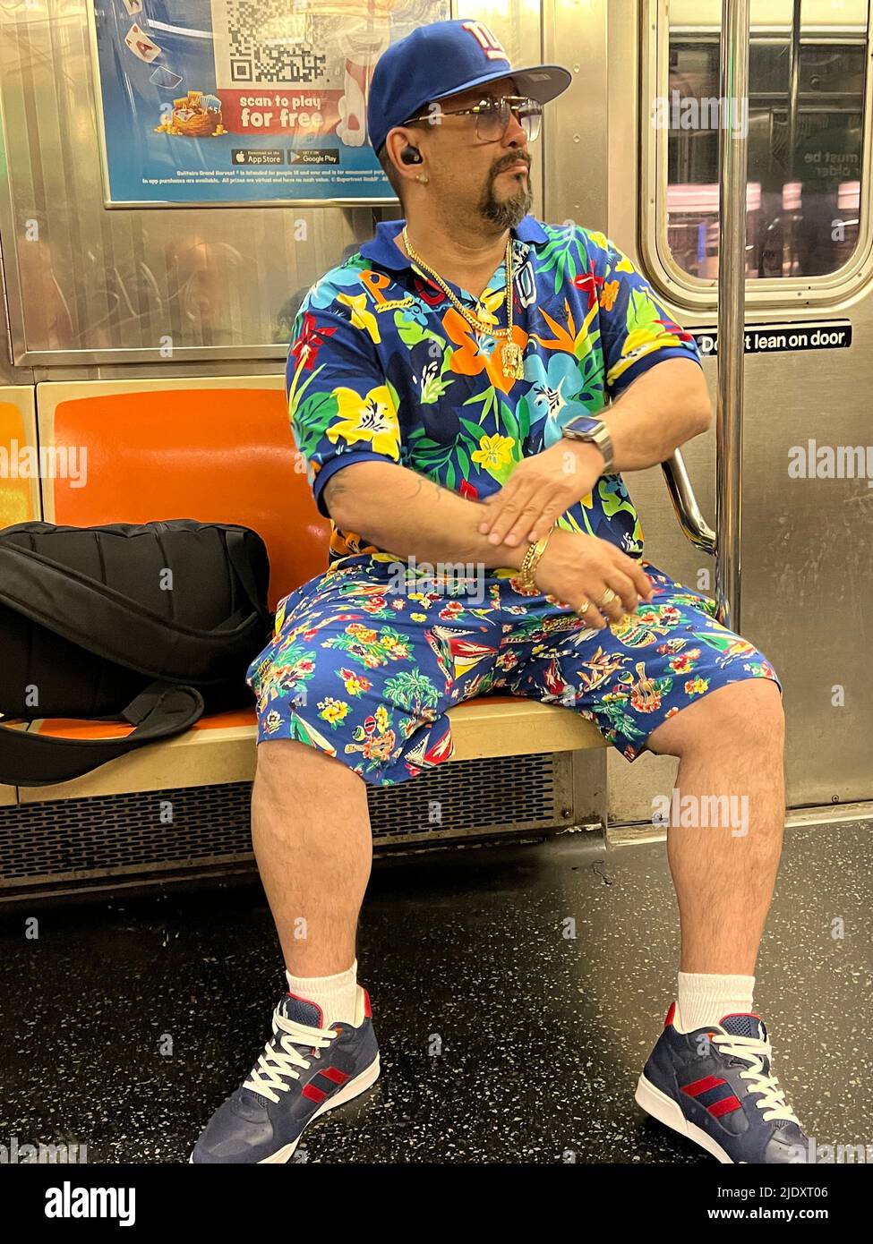 Man wearing fashionable colorful "islandish" clothes riding a subway ...